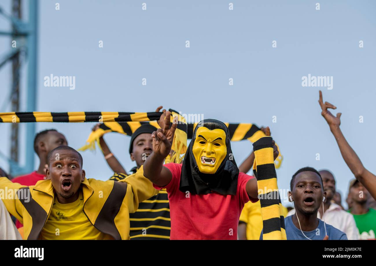 A stream of football fans cheering at a game in Rwanda while wearing ...