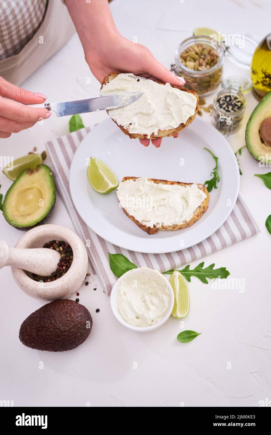 Avocado and cream cheese toasts preparation - Woman smearing cheese on ...