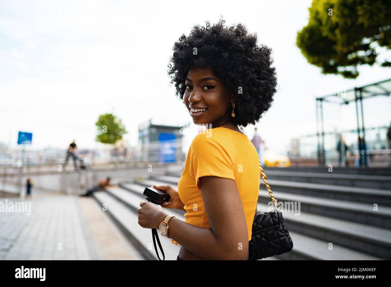 Smiling African american woman using professional camera at a street ...