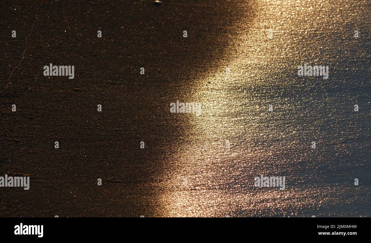 Wet and dry beach in colors of sunset Stock Photo - Alamy