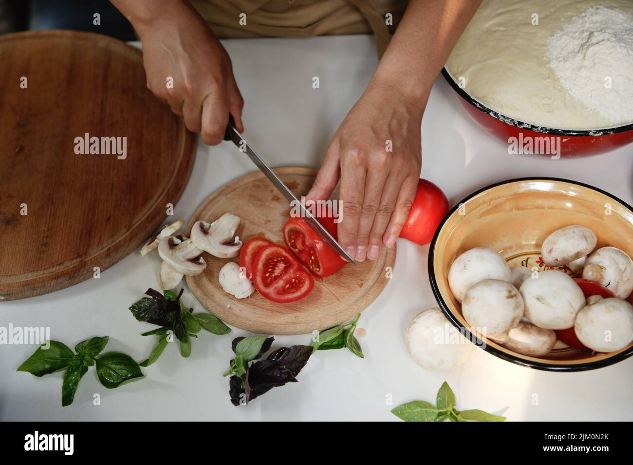 Chef hands cut fresh tomatoes with kitchen knife on chopping board ...