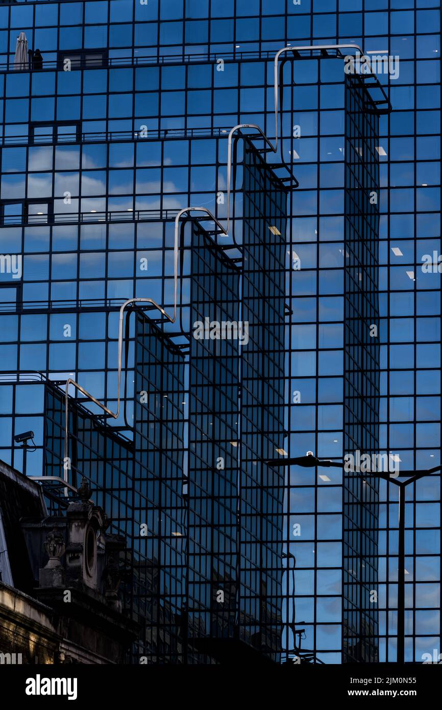 A blue cloudy sky reflected on the glass windows of a modern building ...