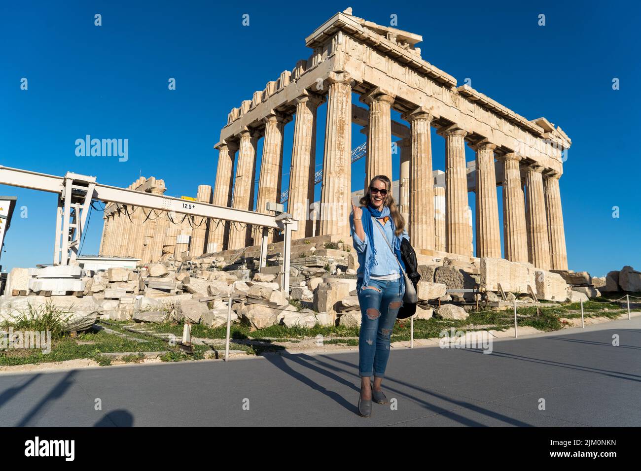 A vertical shot of a Caucasian blonde woman posing in front of ...