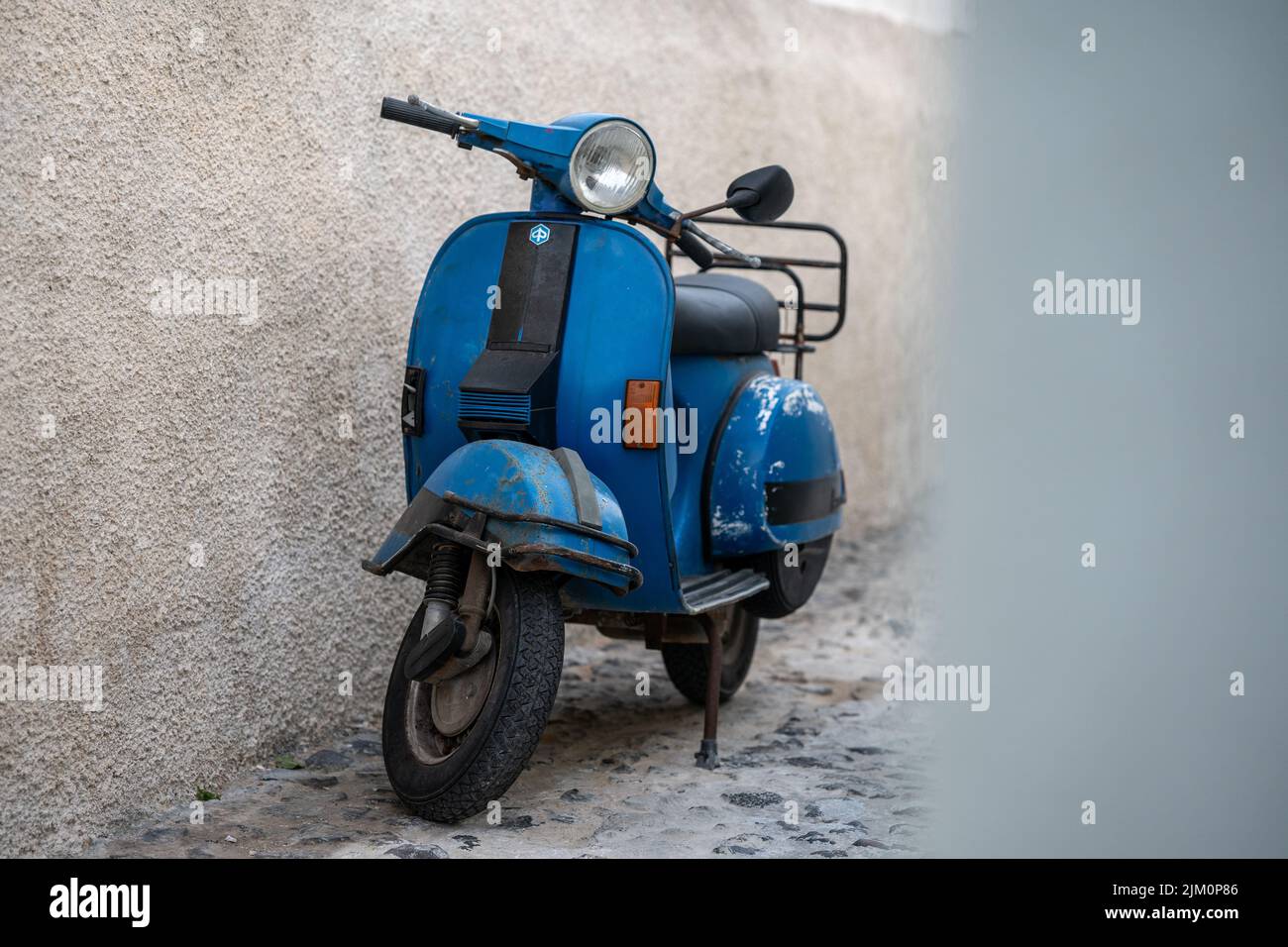 A blue vespa motorcycle parked near a wall Stock Photo - Alamy