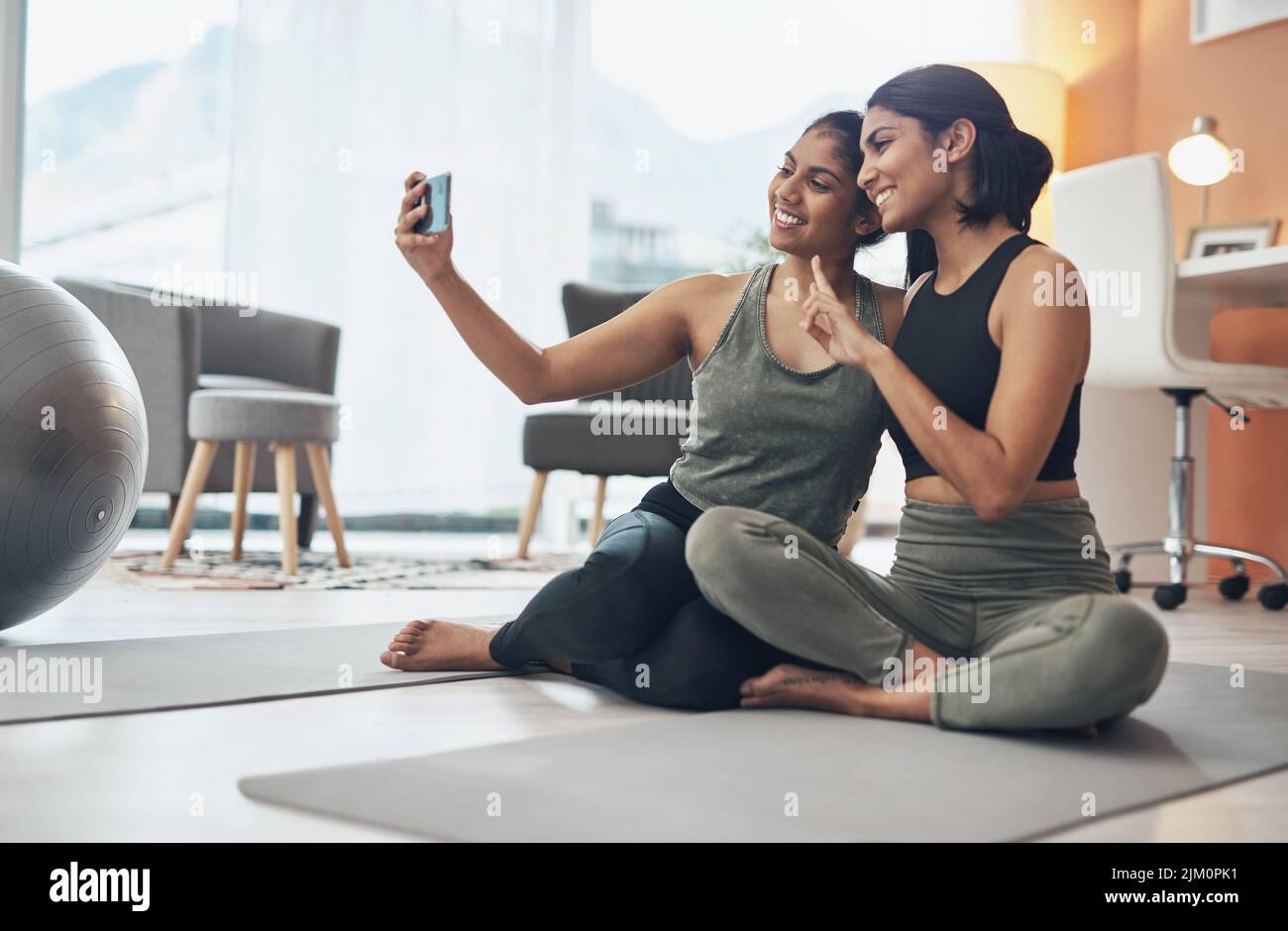 Lets take a selfie before we workout. two young women taking a selfie while sitting at home in ...