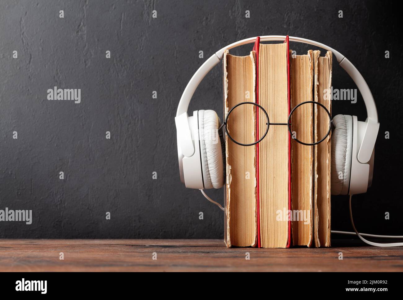 Old books, headphones and eyeglasses on wooden table and blackboard for ...