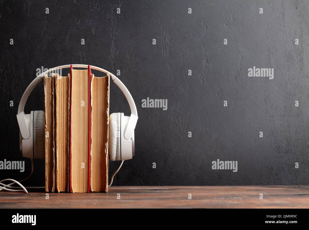Old books and headphones on wooden table and blackboard for copy space ...