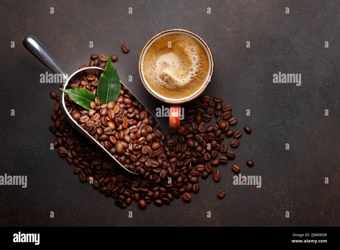 Roasted coffee beans in scoop and cup of espresso. Flat lay on stone ...