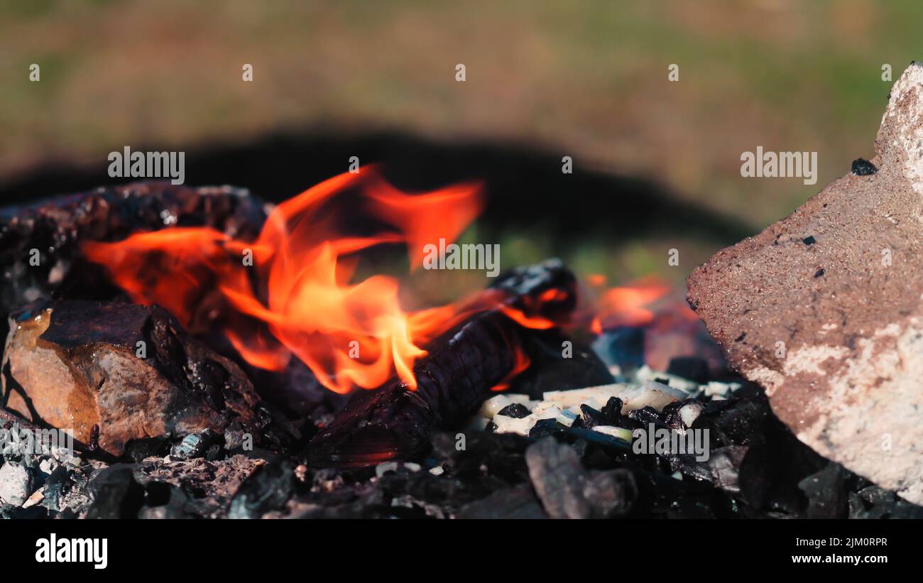 A closeup of a fire burning outdoors with flames coming out of it on a ...