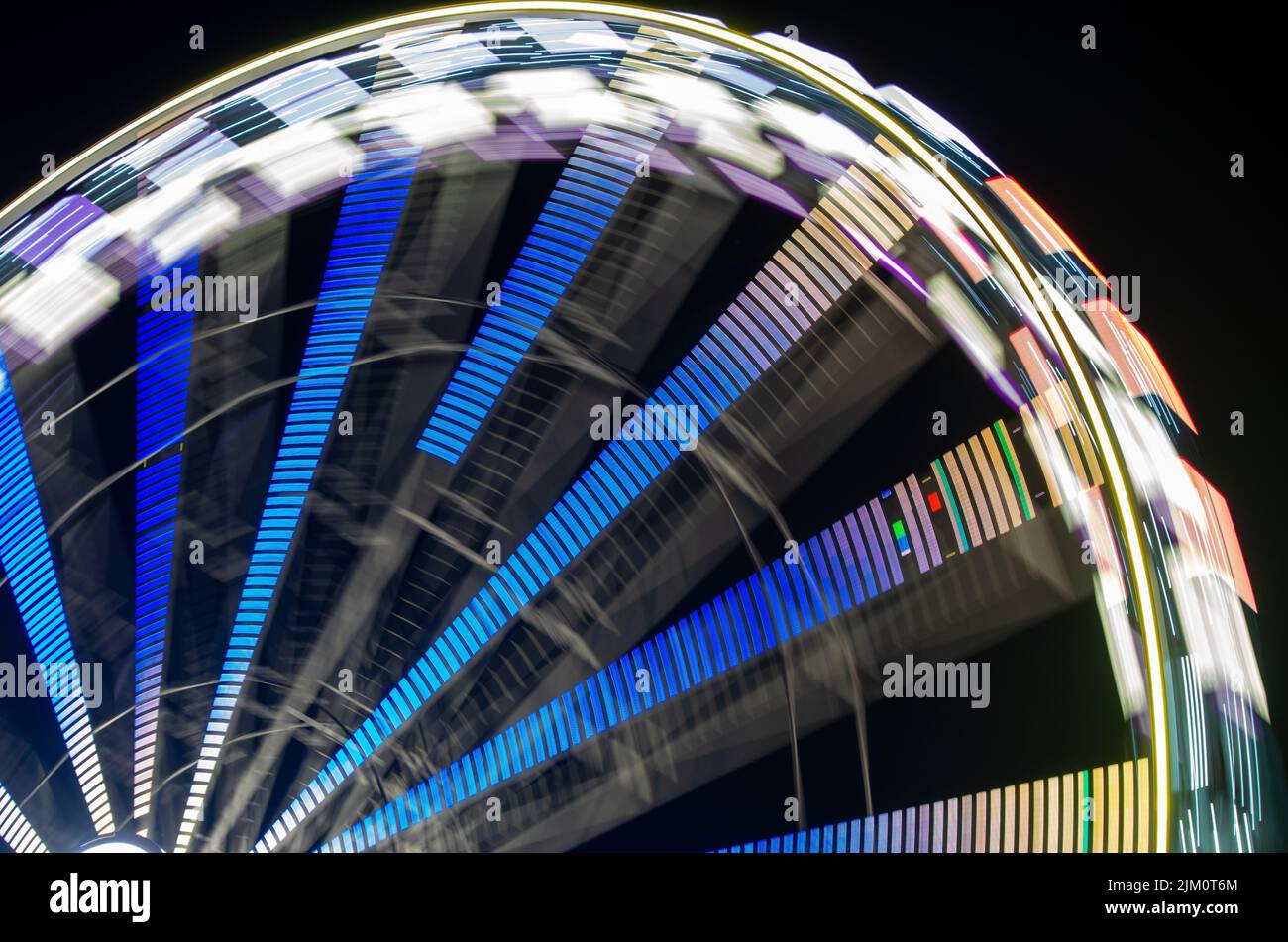 A low angle shot of a spinning illuminated Ferris wheel in a night sky ...
