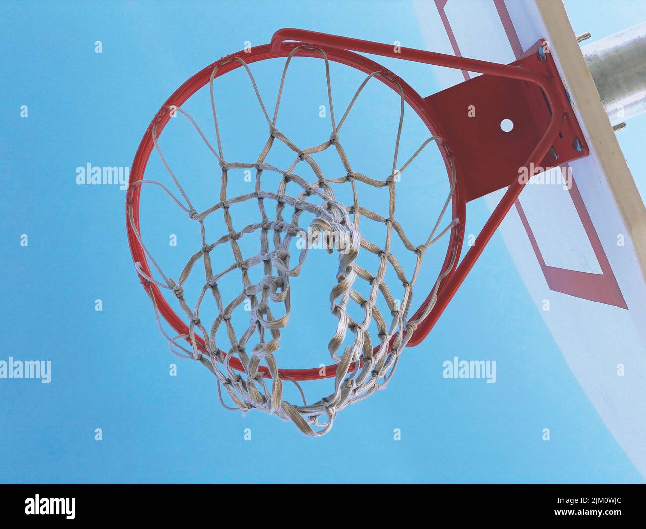 A low angle shot of a red basketball hoop on a blue sky background ...
