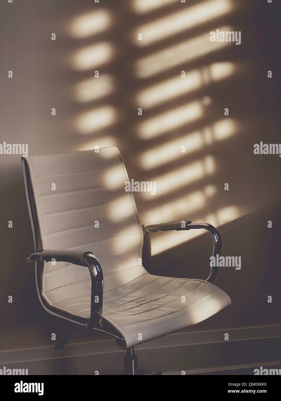 A vertical shot of a white chair near a window with light shadows Stock ...