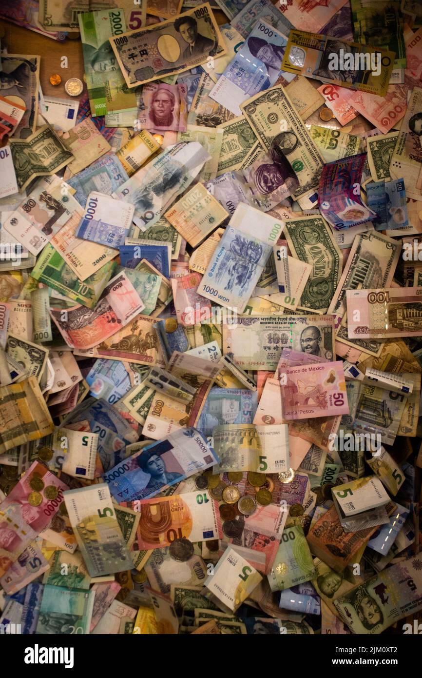 A vertical shot of a pile of banknotes from different countries ...