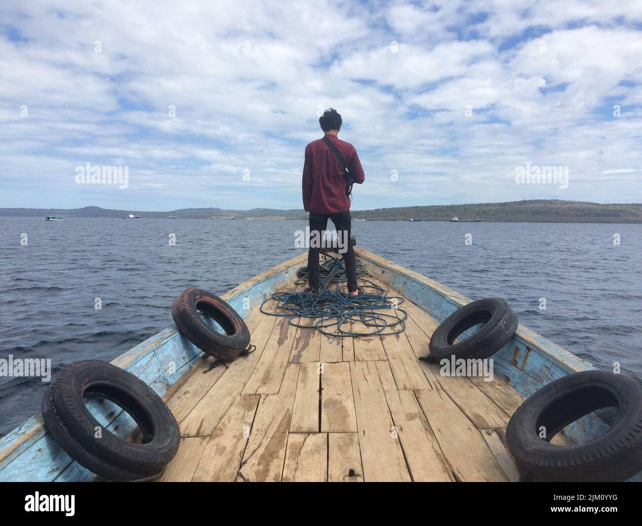 A man on the edge of a boat facing the sea on a cloudy morning Stock ...