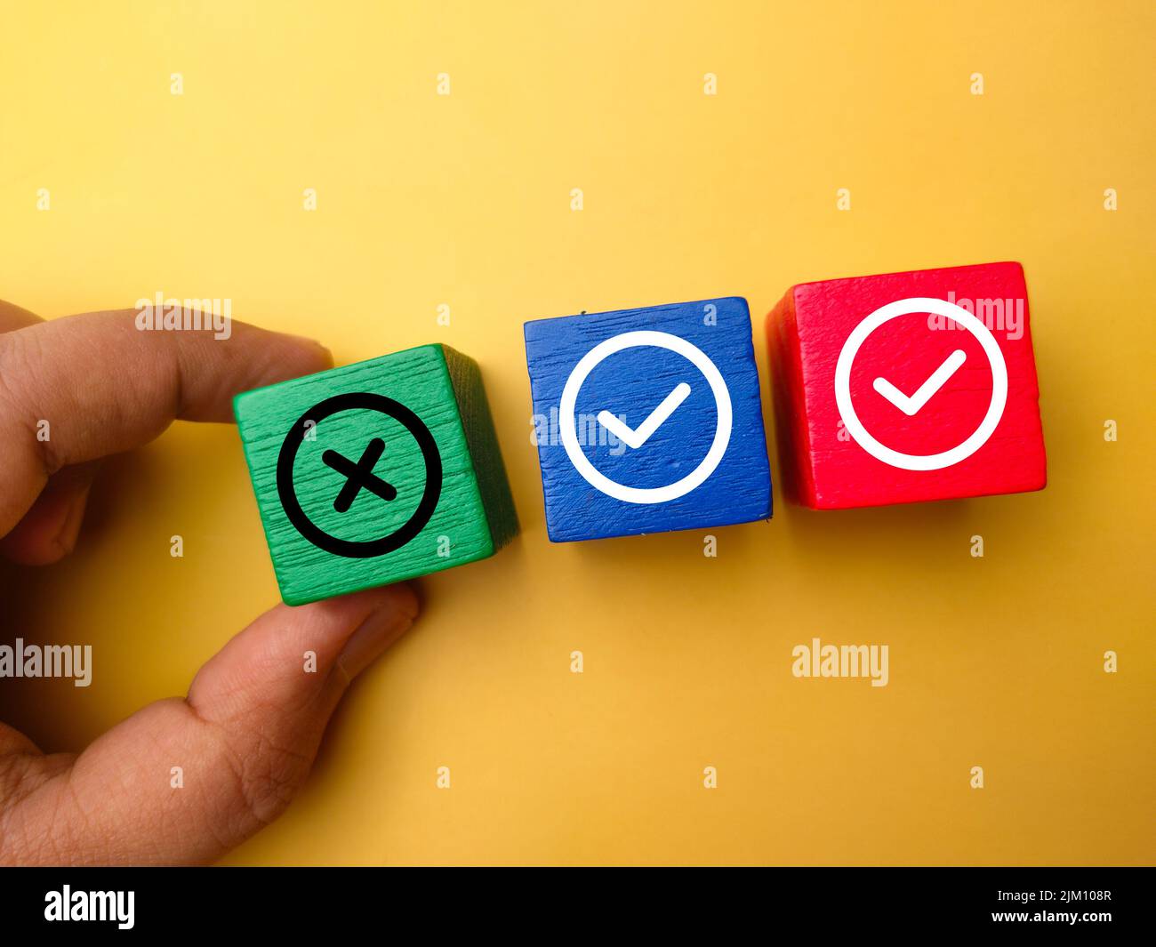 Hand holding colored block with the symbol wrong and correct on yellow ...