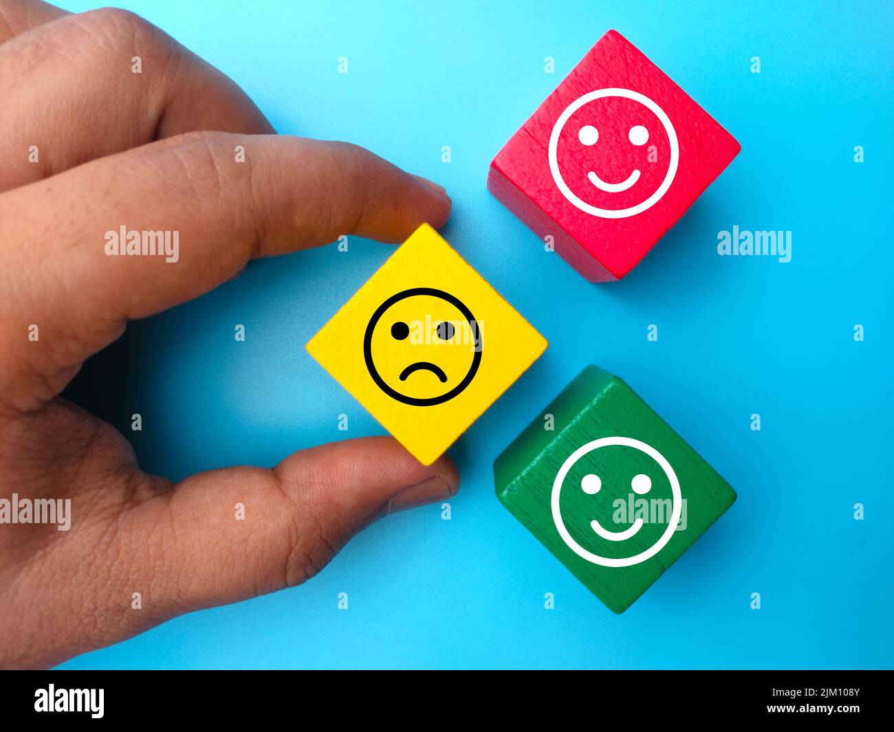 Hand holding colored wooden cube with expression unhappy and happy ...