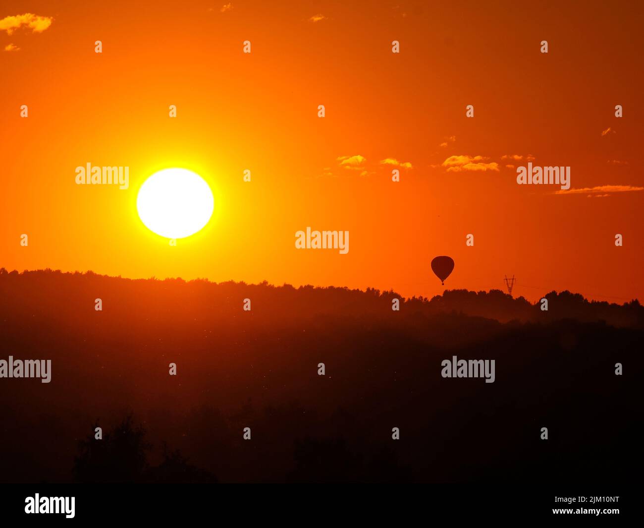 Sunset landscape with the setting sun and the silhouette of a hot air ...
