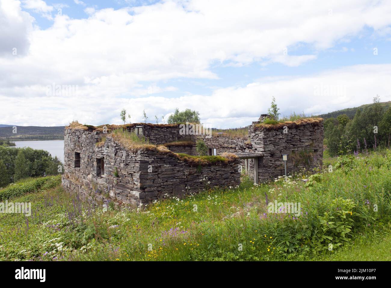 Old abandoned buildings, slate stones in rural area. Meadows, plants ...