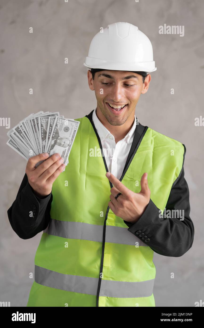 Young muslim builder man engineer wearing safety helmet holding money ...