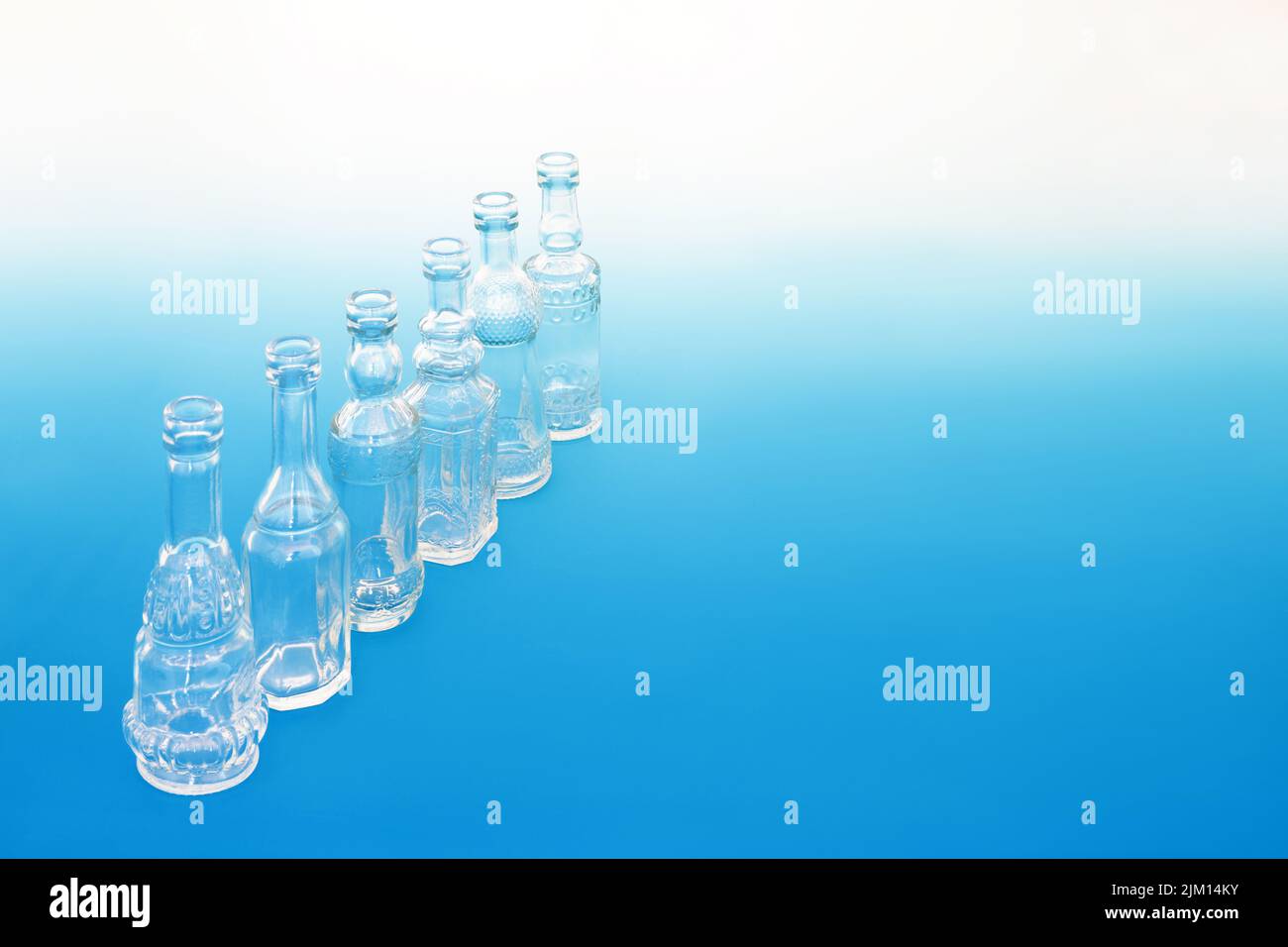 Old fashioned glass bottles in a diagonal line on gradient blue white ...