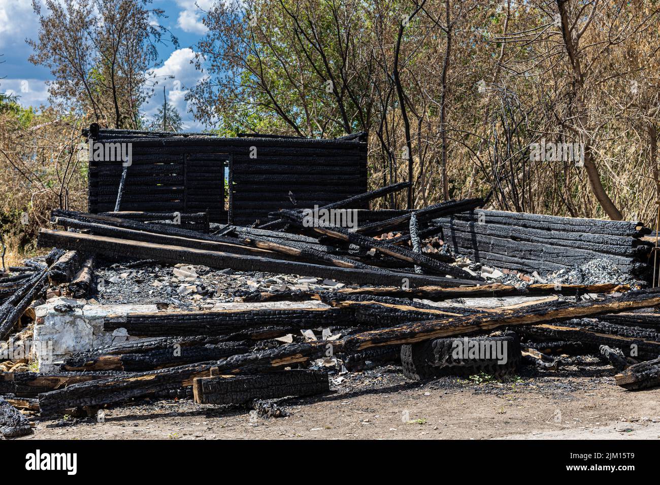 the remains of a burnt log house on the background of nature Stock ...