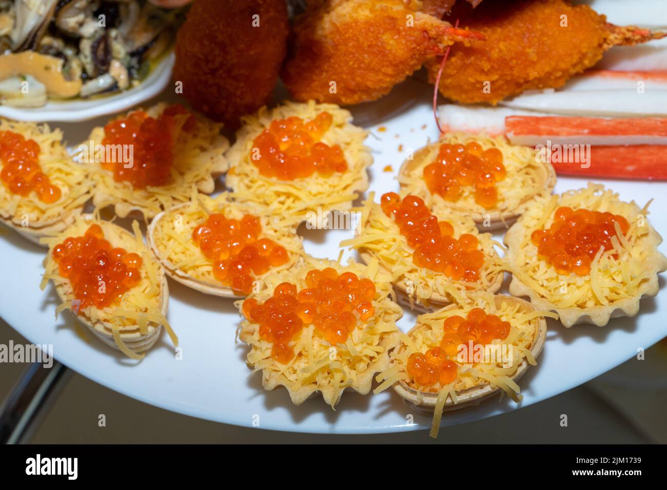 Red caviar and grated cheese in small dough baskets. A delicious cold ...
