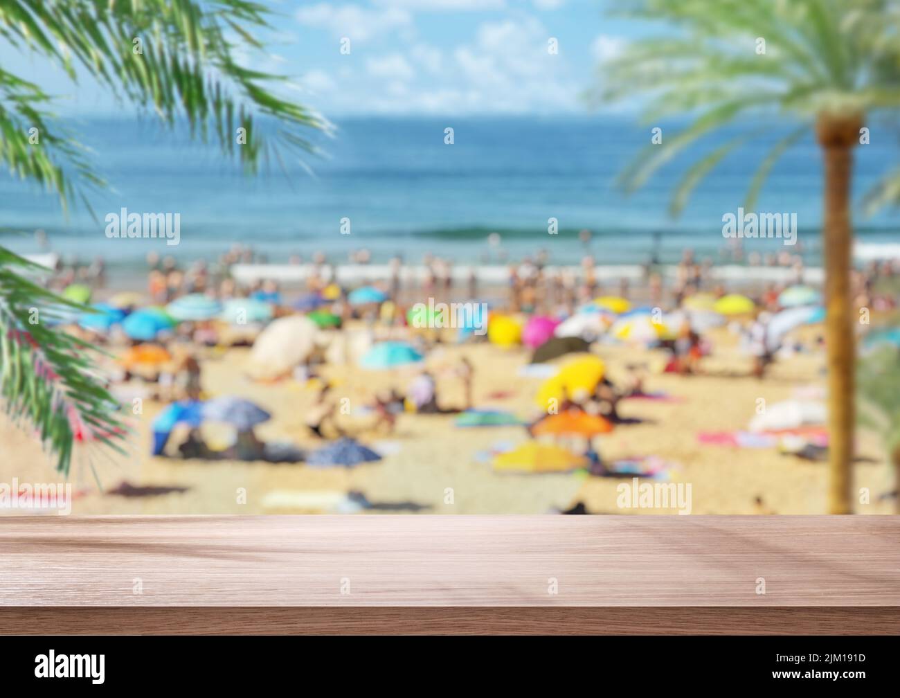 Empty table top and blurred photo of crowded ocean beach in the summer ...