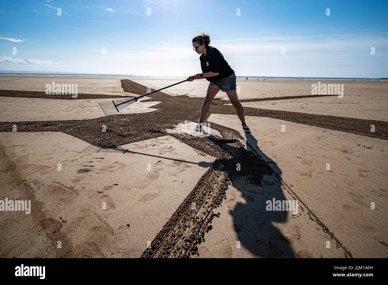 EDITORIAL USE ONLY A person rakes the sand to create a 75-metre piece ...