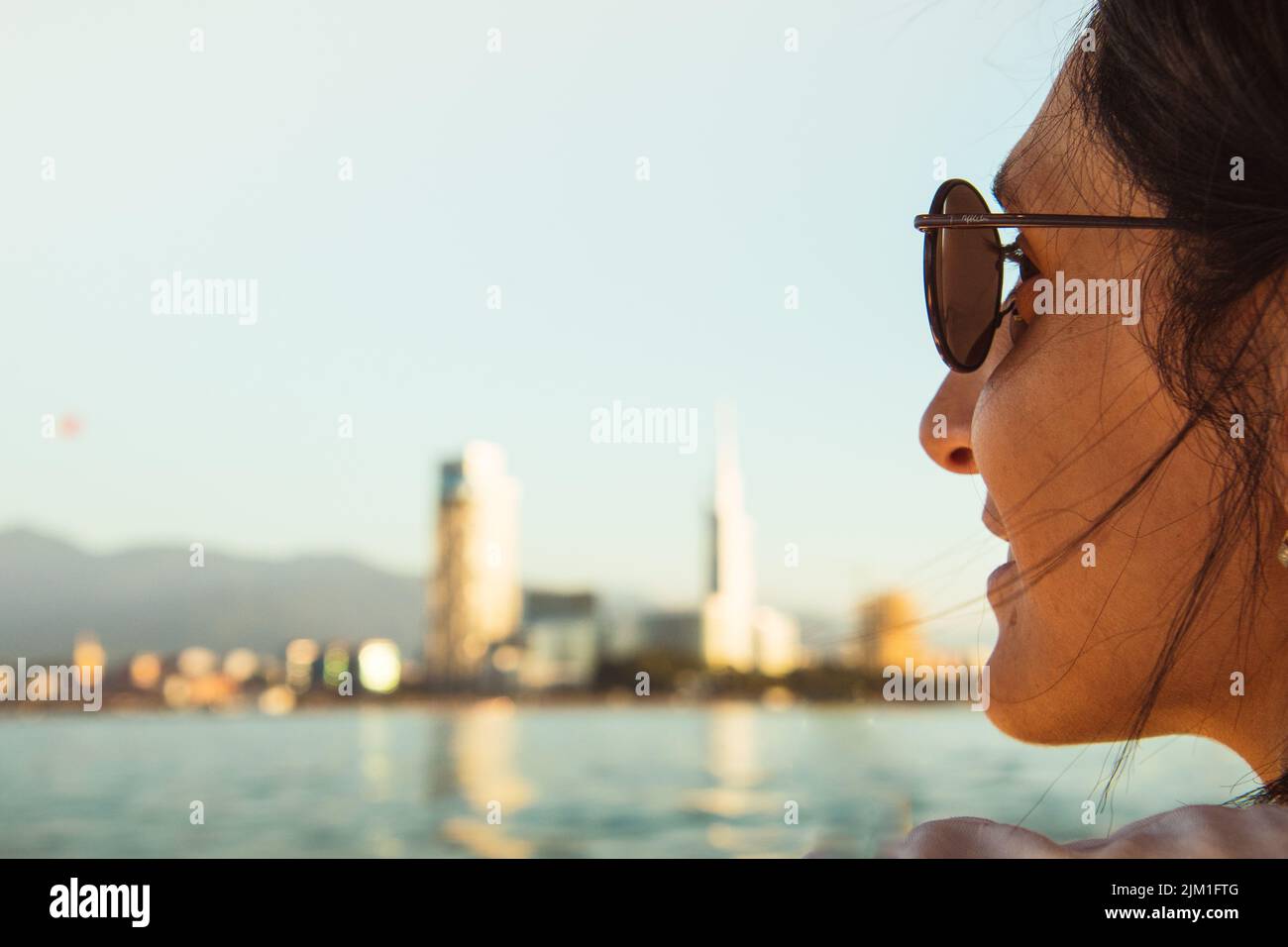 Tourist Woman sits on the boat and looks to scenic view of Batumi and ...