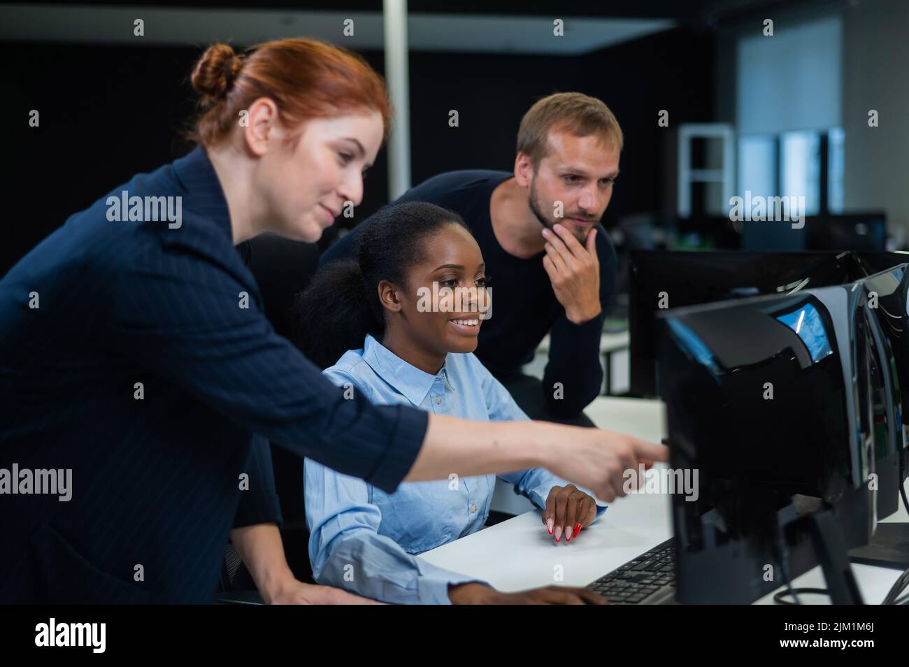 Colleagues discuss work. African young woman, caucasian and red-haired ...
