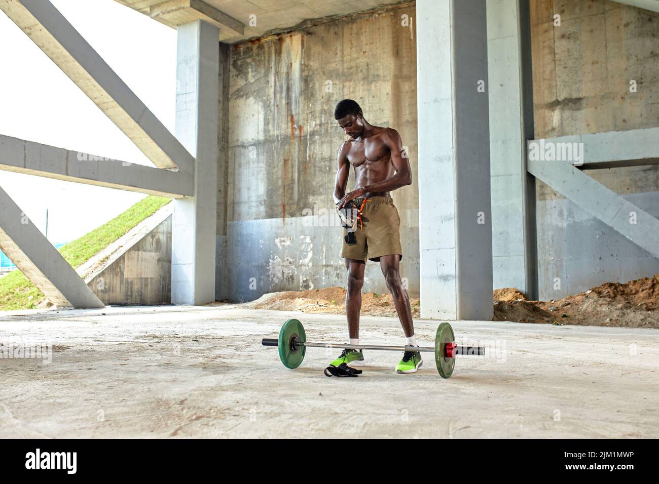 Athletic black young man lifting a heavy-weight barbell in outdoor gym ...