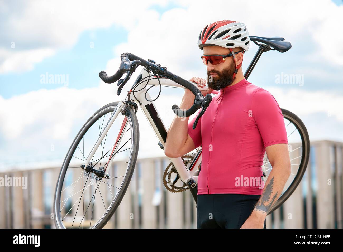 Portrait of a cyclist standing under a bridge with a bicycle in his ...