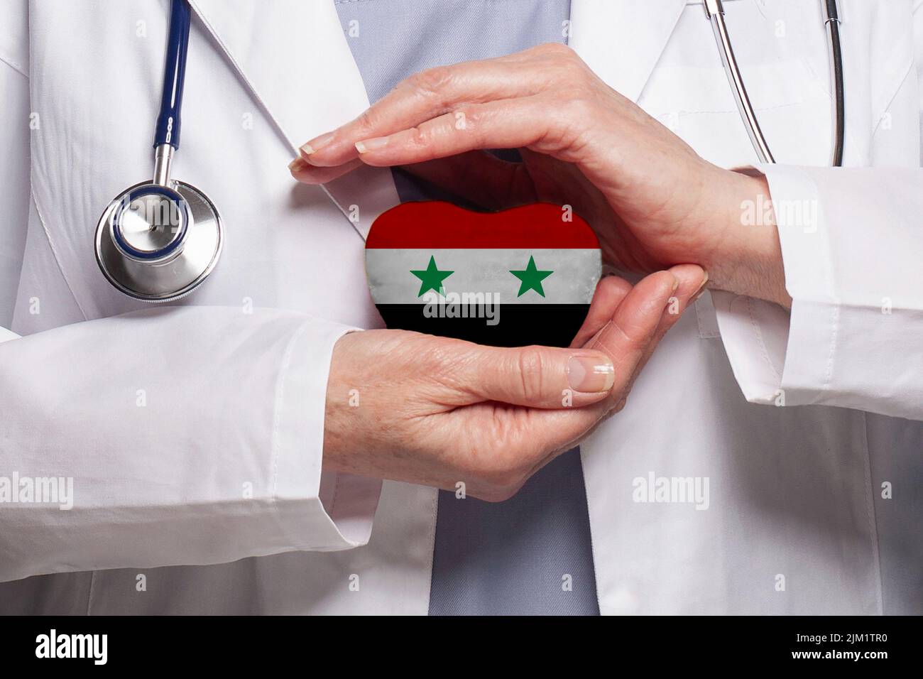 Syrian doctor holding heart with flag of Syria background. Healthcare ...