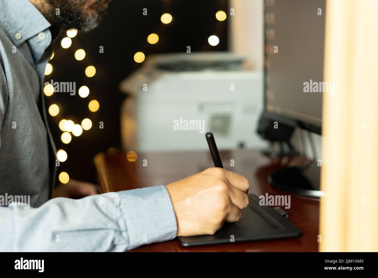Young graphic designer sitting at his workspace using digital graphics ...