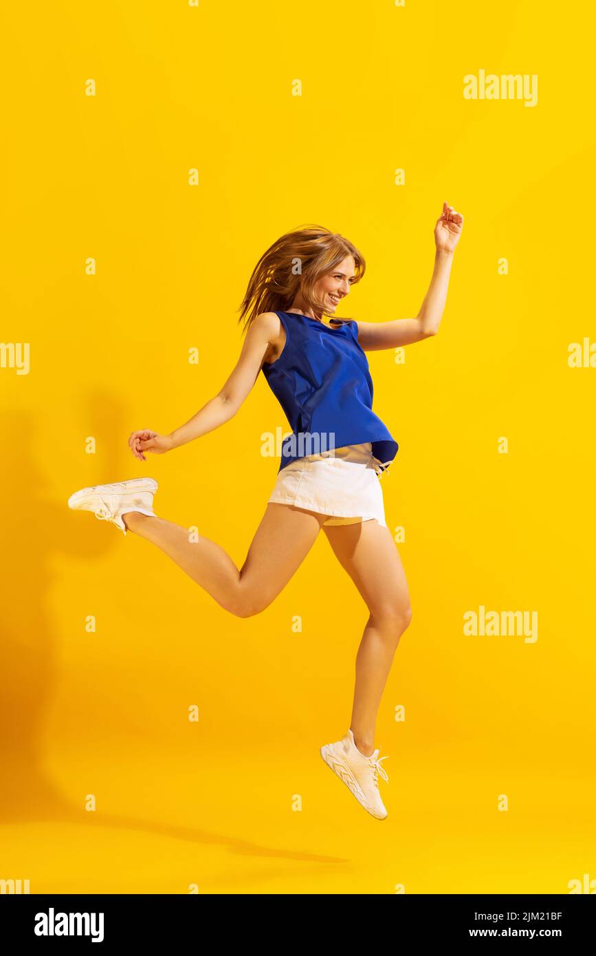 Happy young girl, student jumping isolated on bright yellow background ...