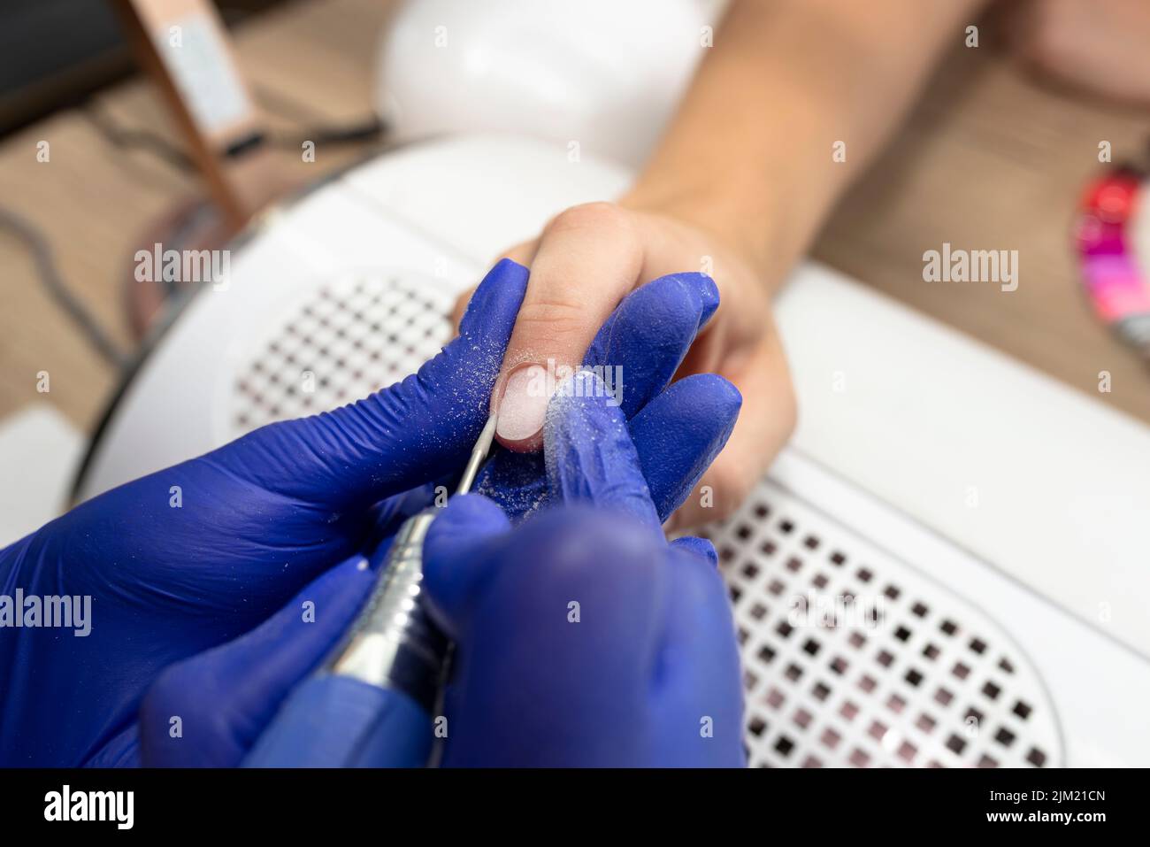 The manicurist cuts the cuticles of the nails with an electric milling ...