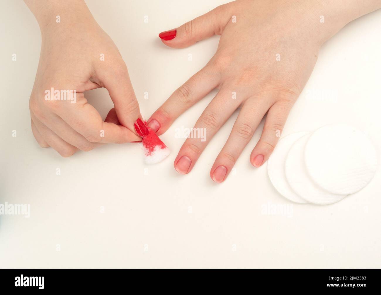 Young woman removes nail polish from her nails with a cotton pad soaked ...