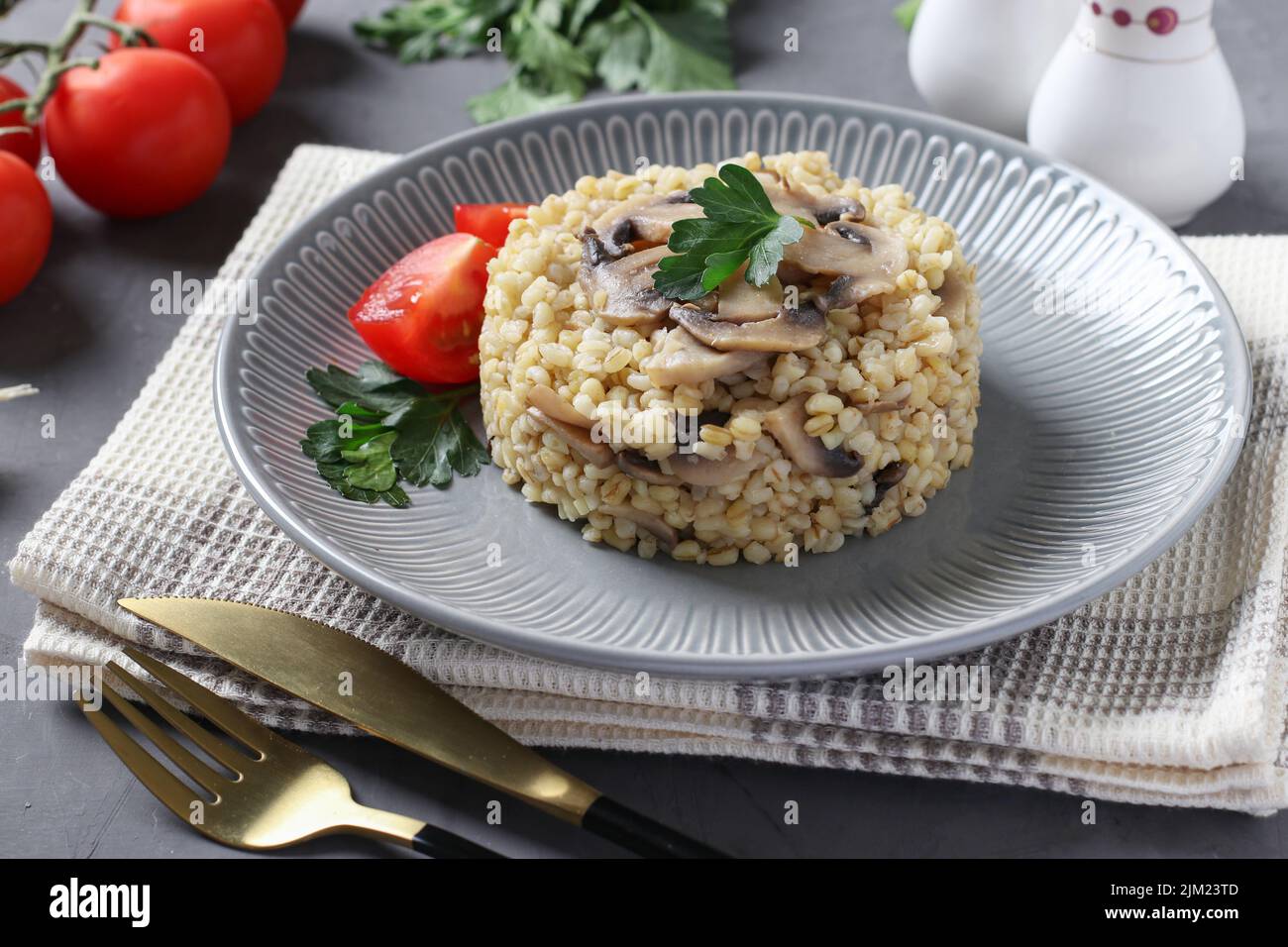 Bulgur garnish with champignons served with tomatoes on gray plate ...