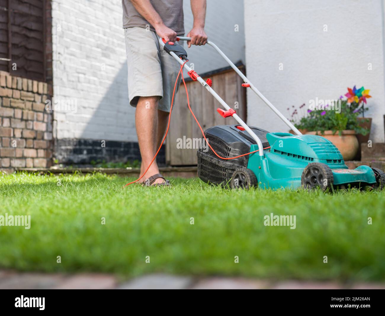 Man cutting grass with lawn mower in yard Stock Photo - Alamy