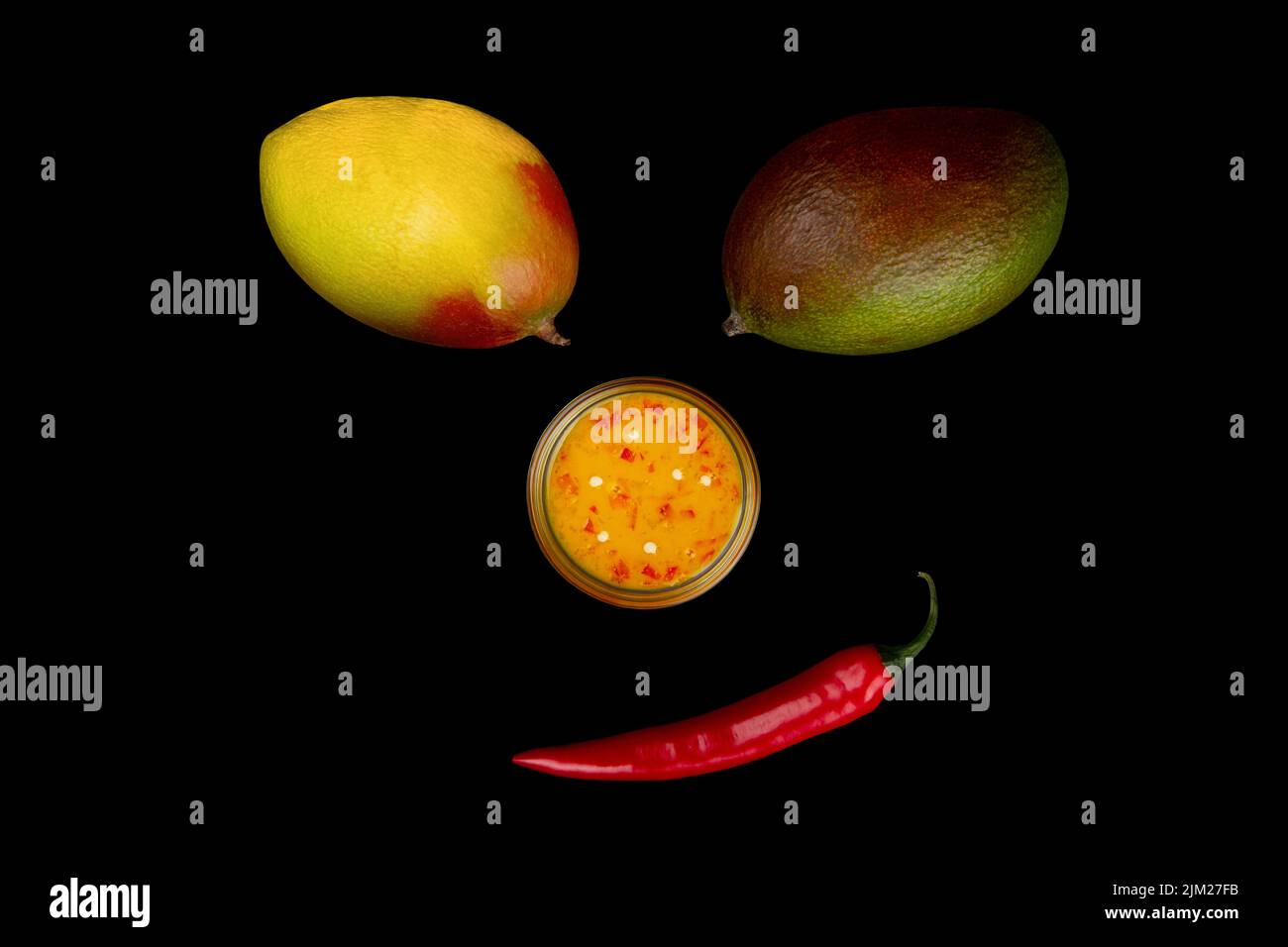 Funny face made of mango, chili and mango chili sauce on black ...