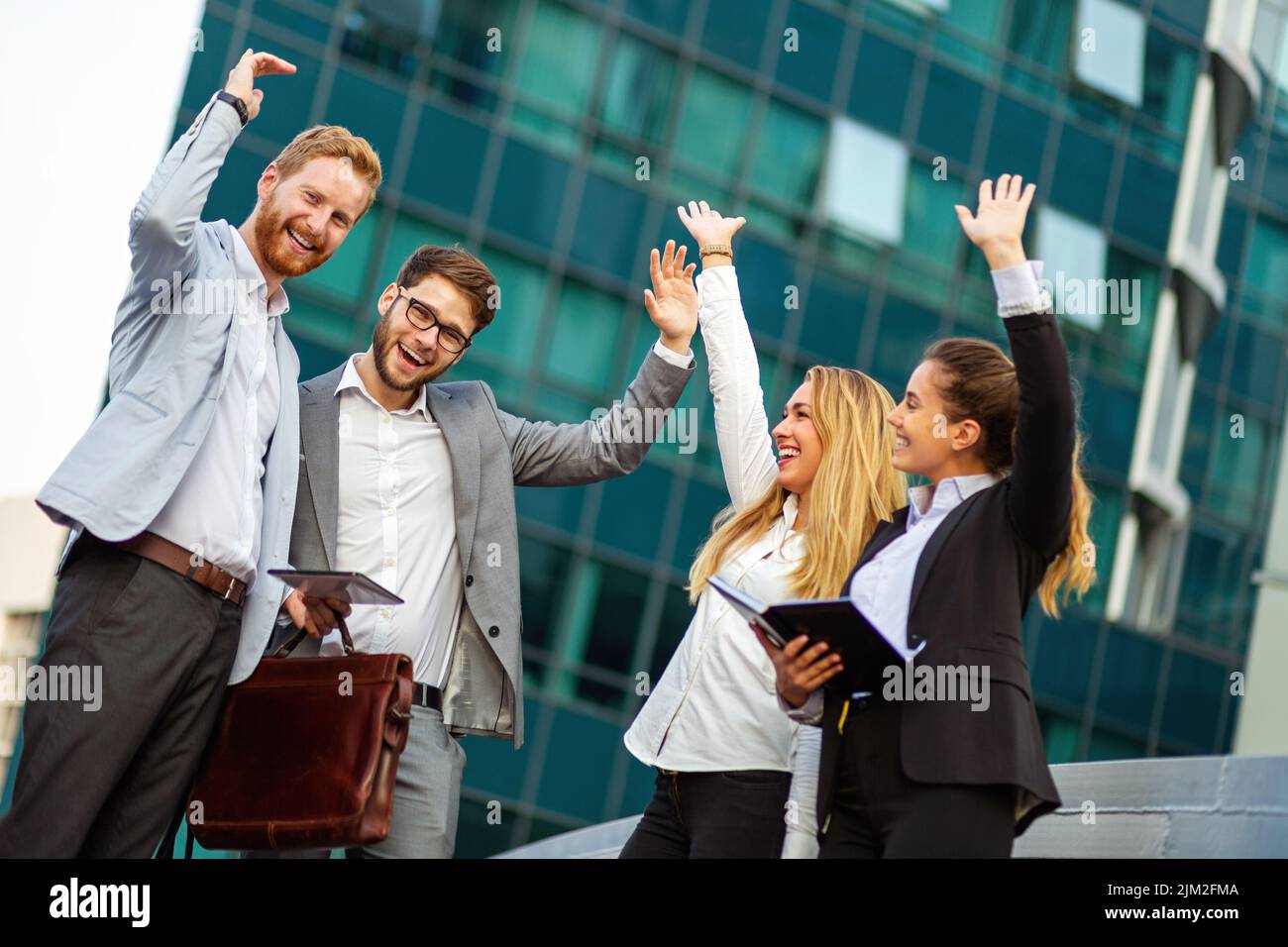 Group of happy successful business people holding their arms up and ...