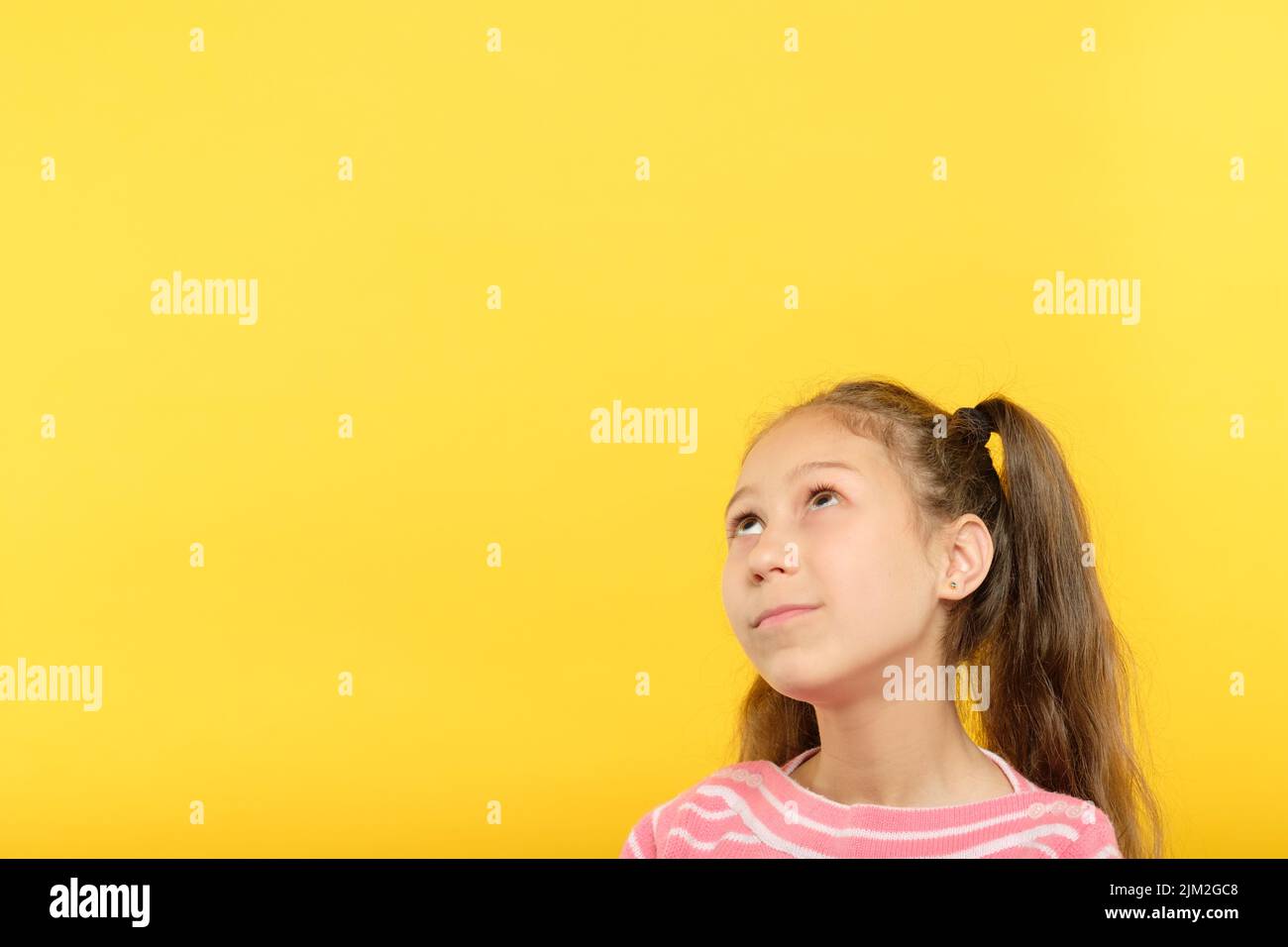 cute girl look up yellow background empty space Stock Photo - Alamy