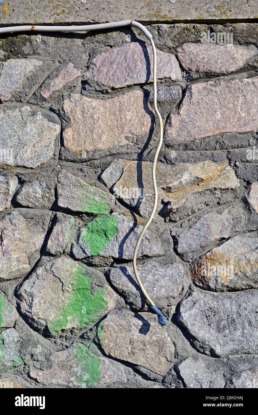 white power electrical cable closeup on stone wall, electrical industry ...