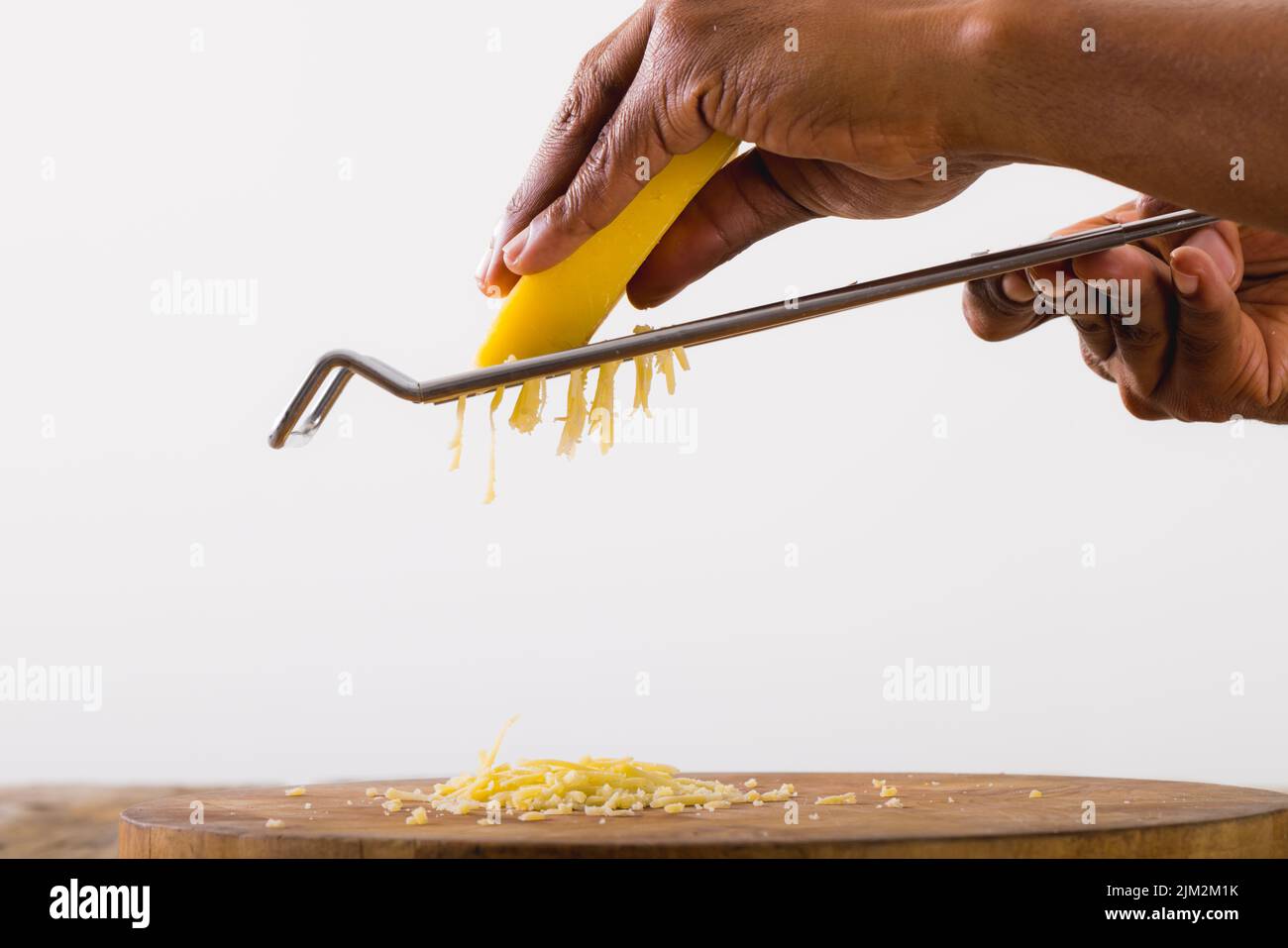 Close-up of african american male chef grating cheese against white ...