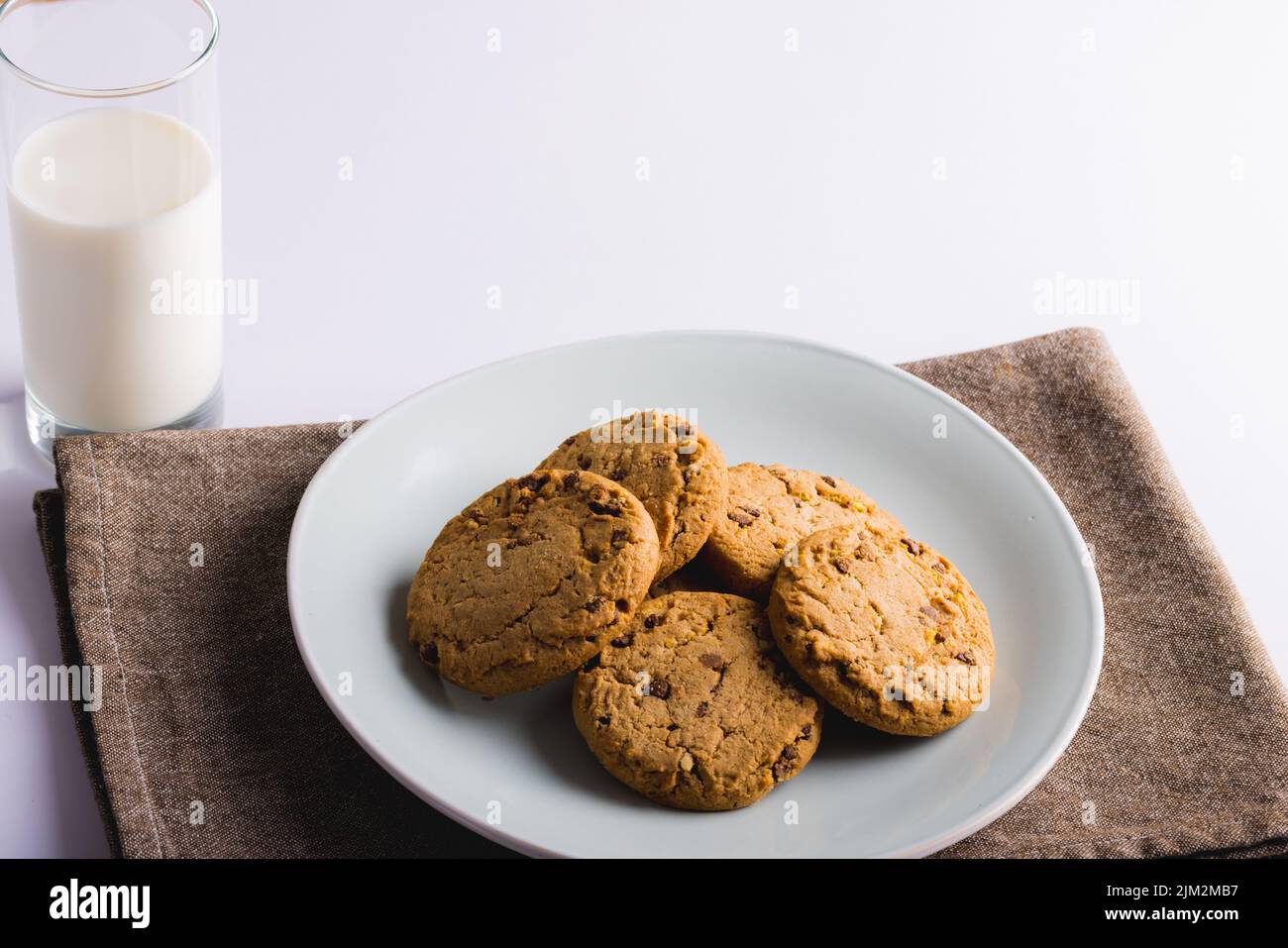 Cookies in plate by milk glass on white background with copy space ...