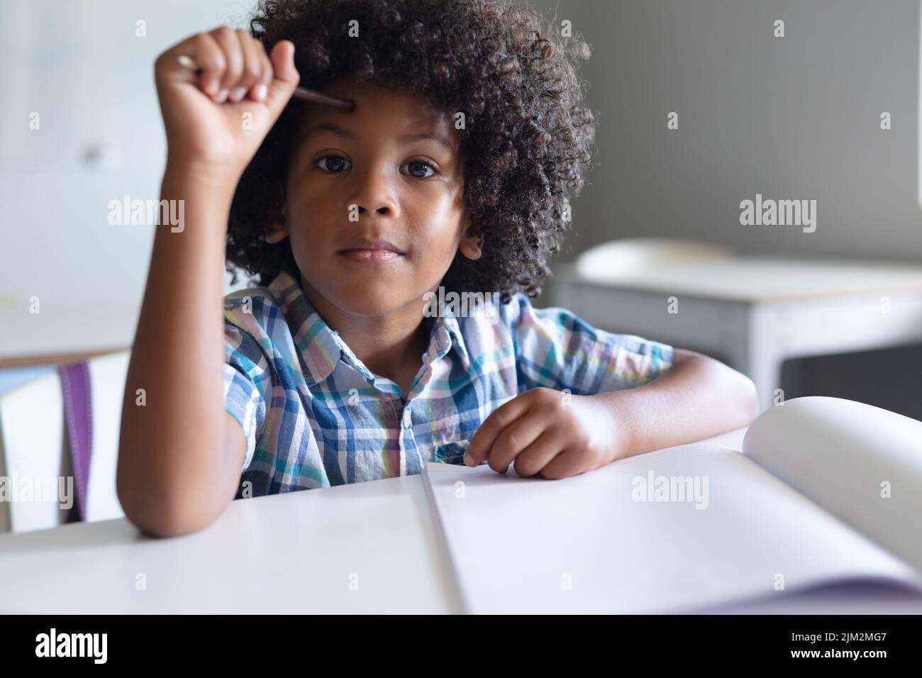 Portrait of african american elementary schoolboy holding pencil while ...