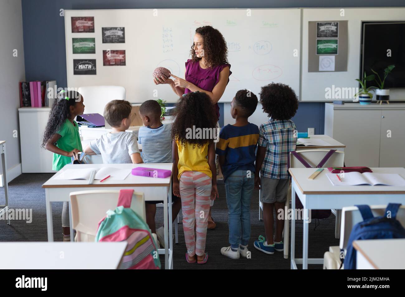 Multiracial elementary school students looking at caucasian young ...