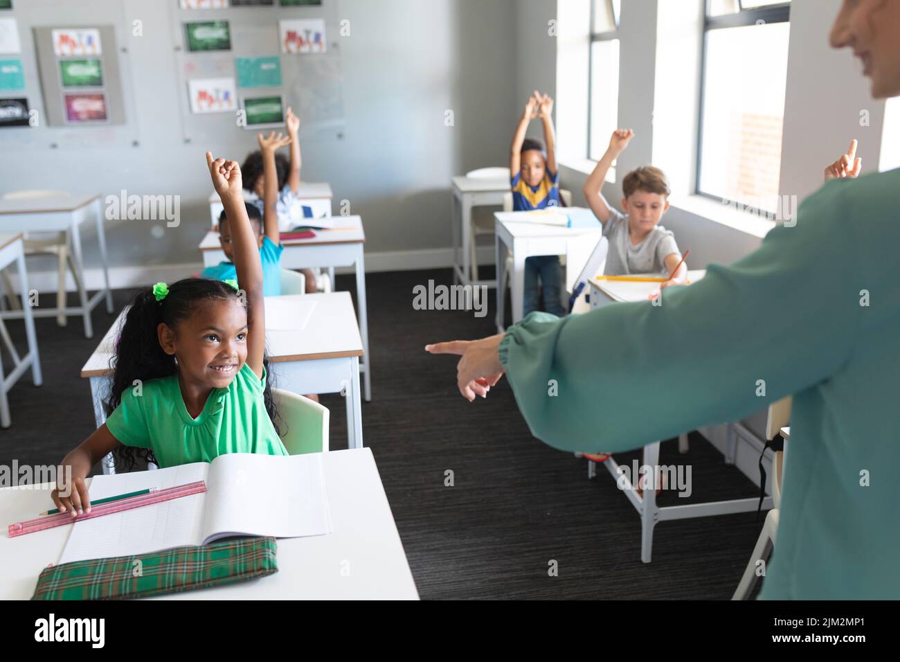 Caucasian young female teacher pointing on african american elementary ...