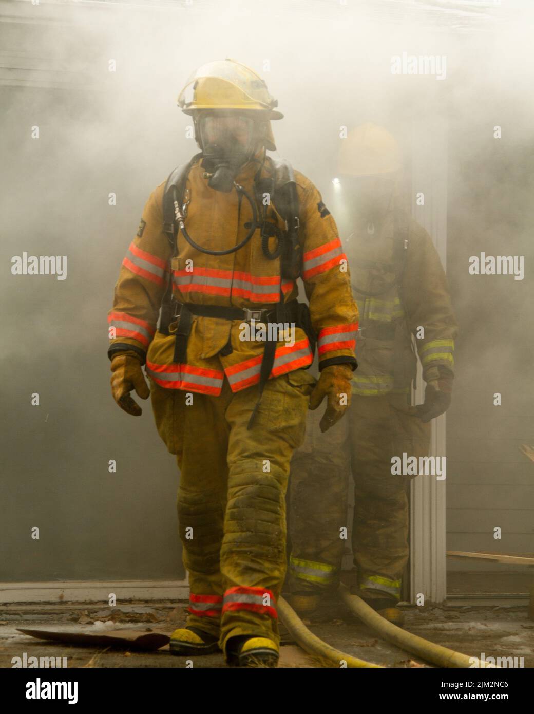 Firefighter exiting a burning building Stock Photo - Alamy