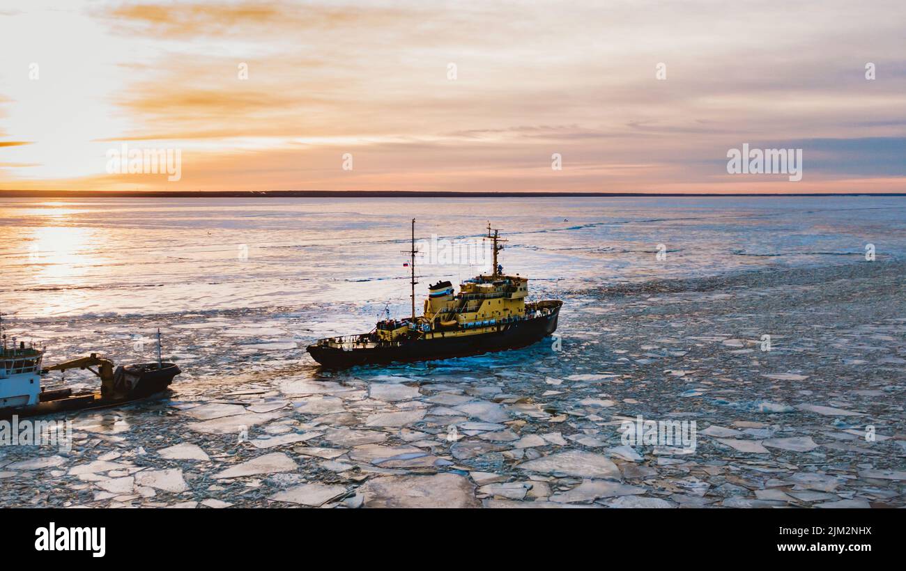 Icebreaker goes on the sea among the blue ice at sunset, aerial view ...
